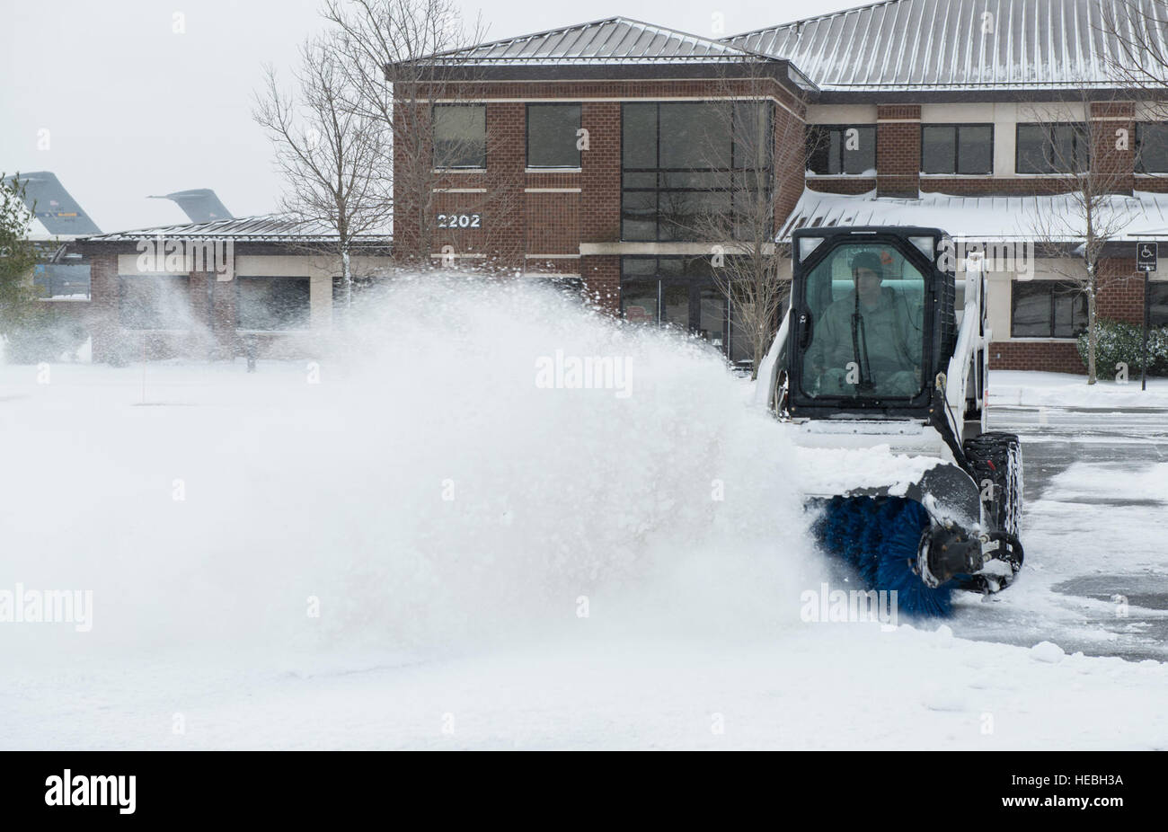An 87th Civil Engineer Squadron Airman clears snow from a parking lot ...