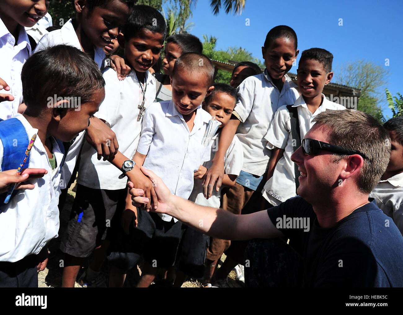 Petty Officer 3rd Class Zim Padgett shakes hands with Timorese students ...