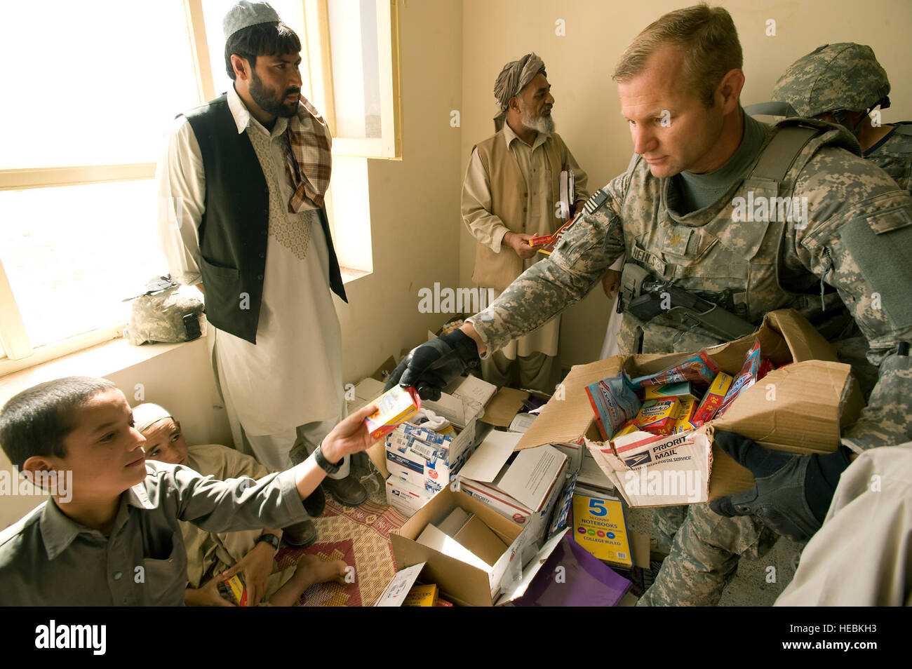Army Maj. Trever Nehls hands a box of crayons to an Afghan boy. The ...