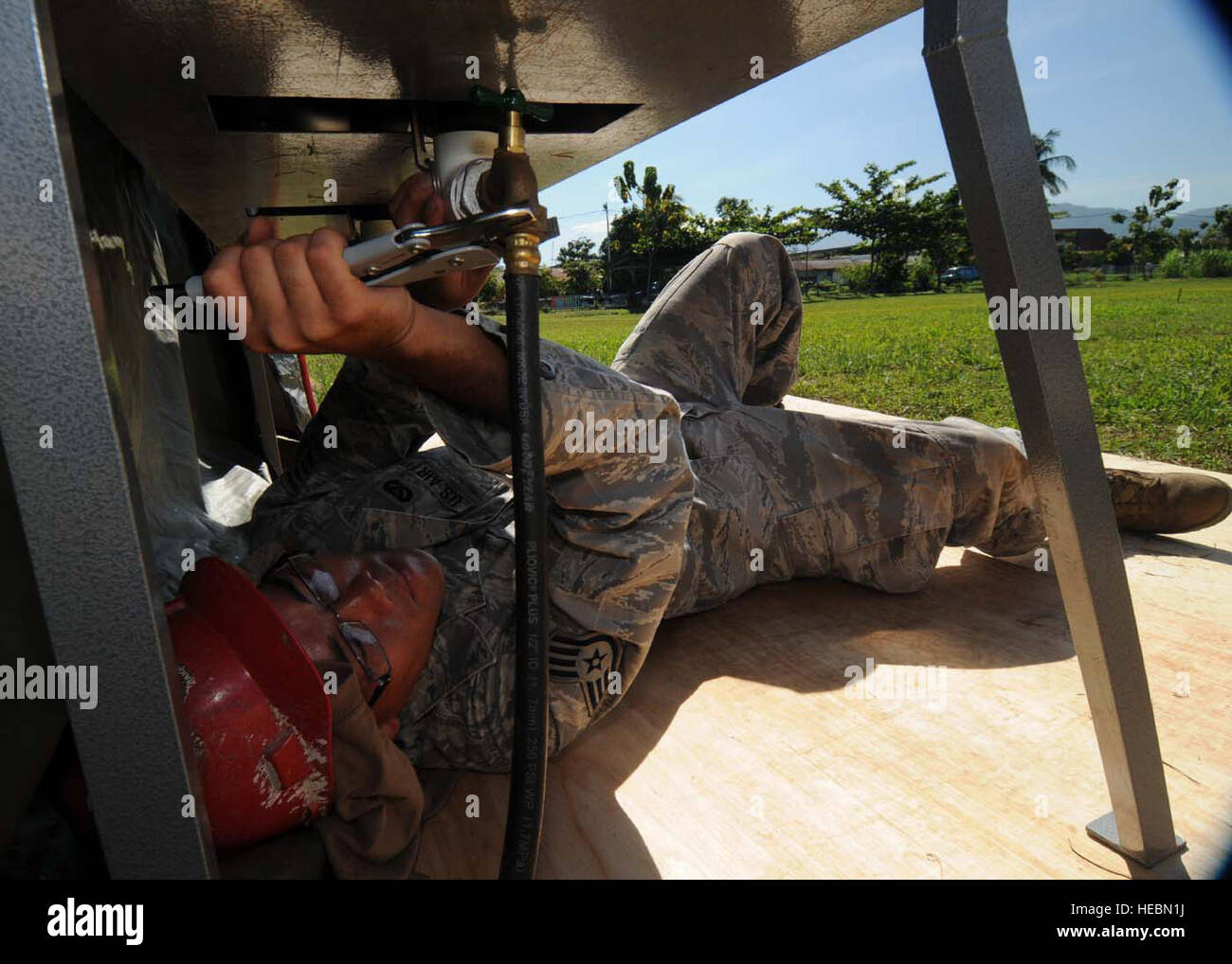 Staff Sgt. Thomas Agee connects a pump to a shower kit to provide ...