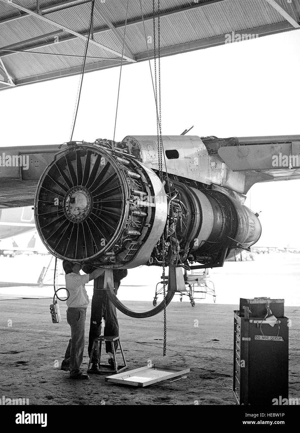 A technician hoists the front engine of a Boeing 707 aircraft into ...