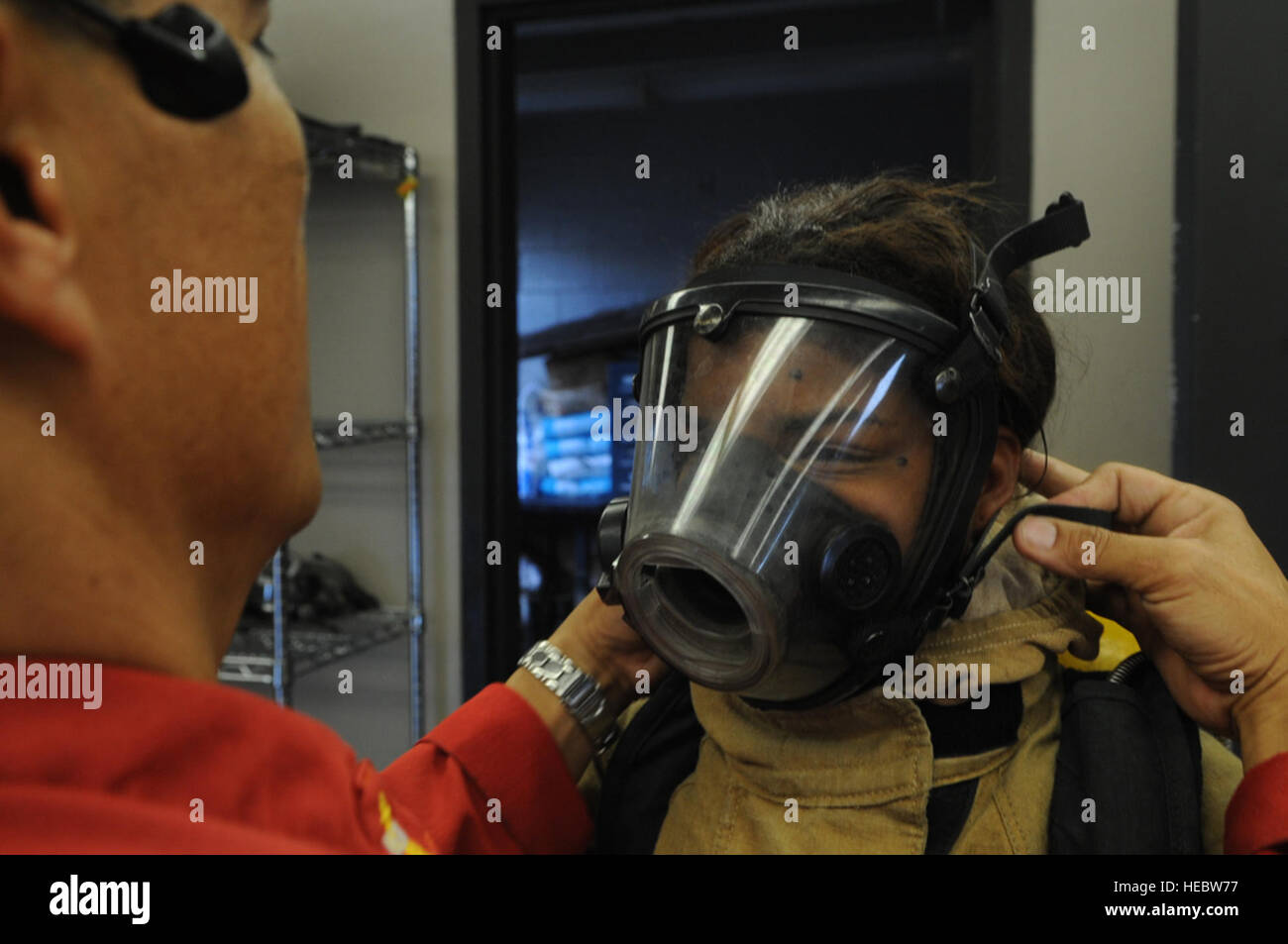 A fire-training instructor fastens the mask of U.S. Navy Seaman Elicia ...