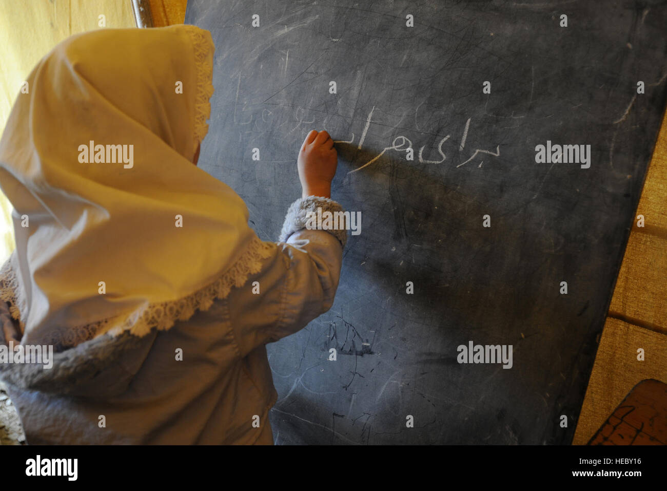 A young Afghan girl practices writing Dari in her classroom, which is ...