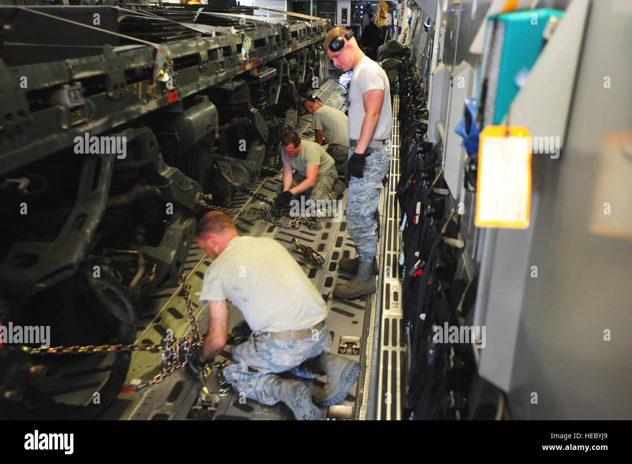 Airmen fasten 25K restraint chains to a 60K Tunner Loader on a C-17 ...