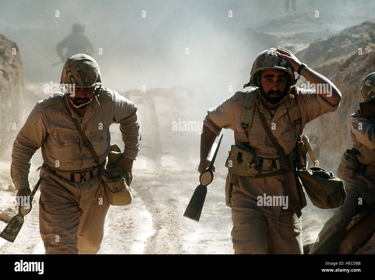 Kuwaiti soldiers carrying pick axes run in a trench during a ...