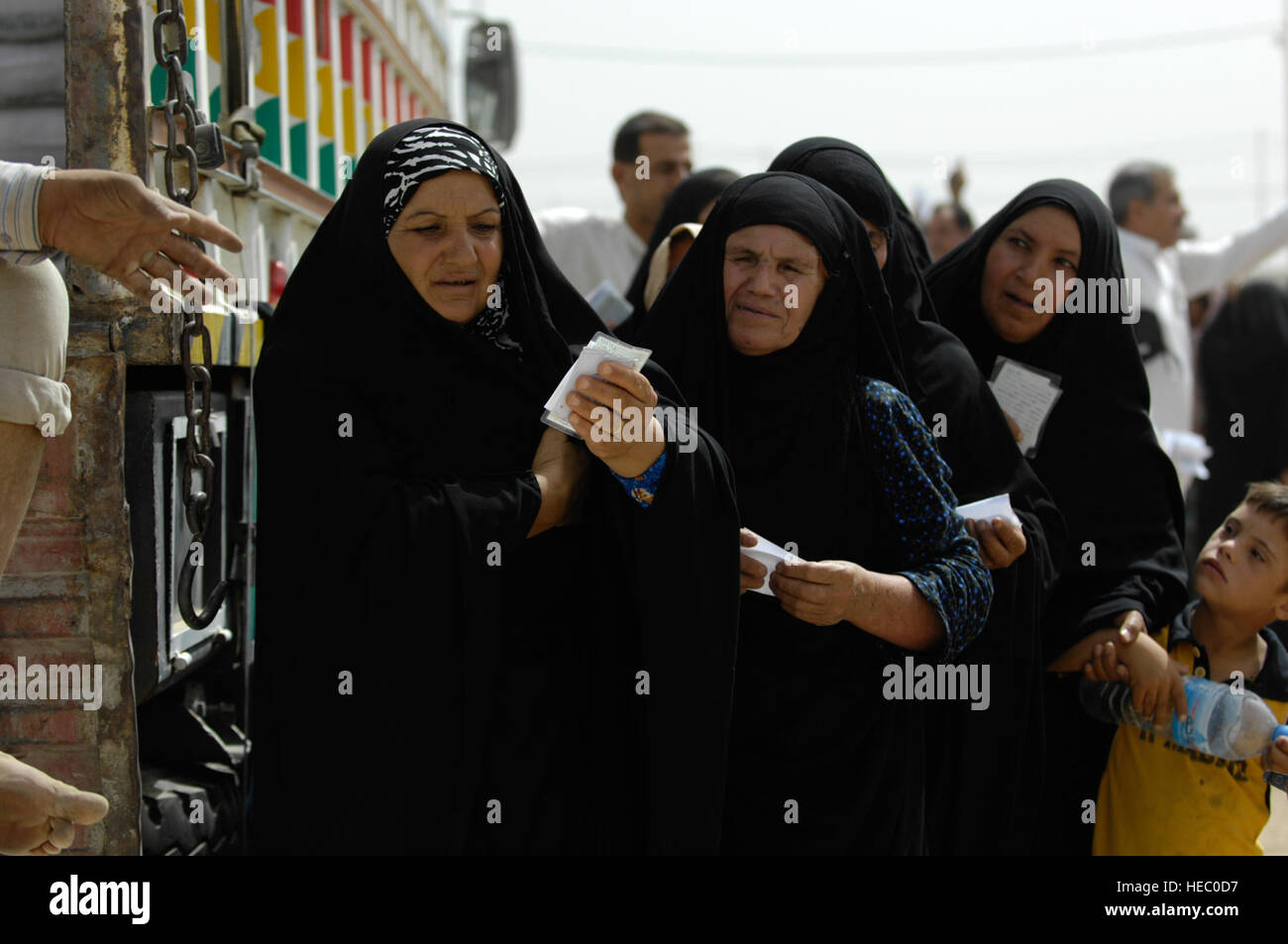 Iraqi women stand in line with their ration cards during a humanitarian ...