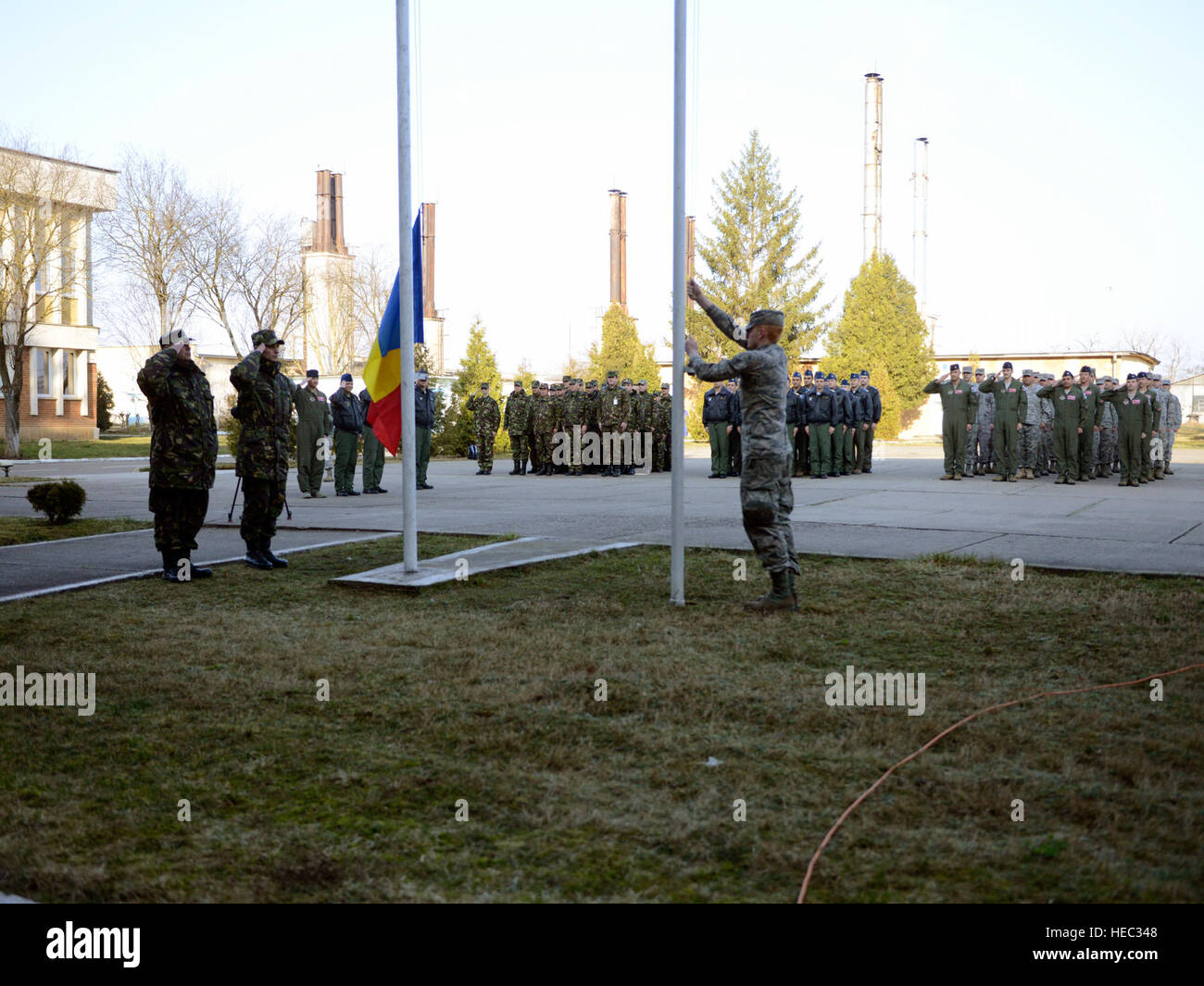 U.S. and Romanian Airmen salute as the American flag is raised during a ...