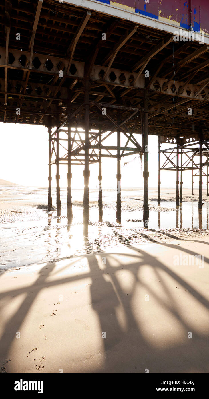 Seaside pier legs silhouetted against empty beach Stock Photo - Alamy