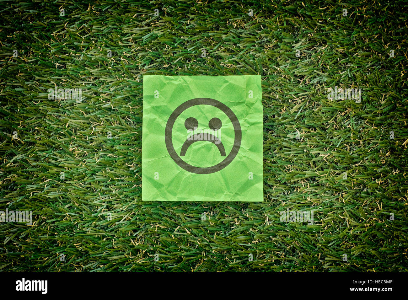 Green paper with sad unhappy face on a green grass. Close up Stock ...