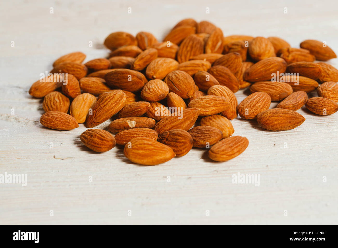 handful of almonds on a white wooden background Stock Photo - Alamy