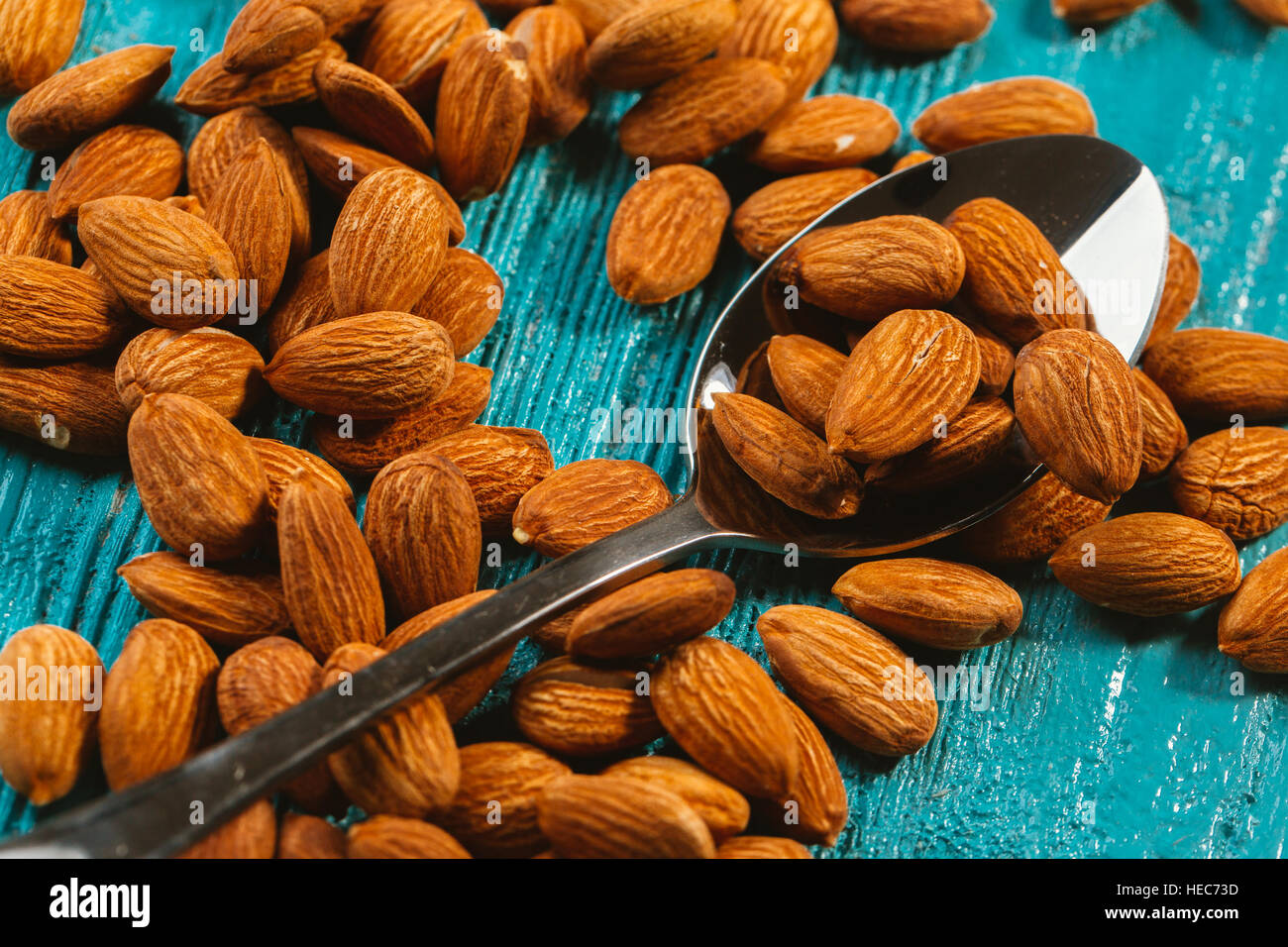 handful of almonds in metal spoon on a blue wooden background Stock ...