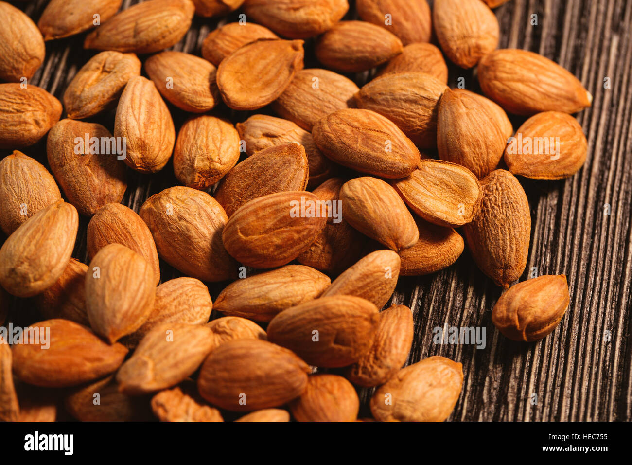 Apricot kernels are scattered on the wooden background Stock Photo - Alamy