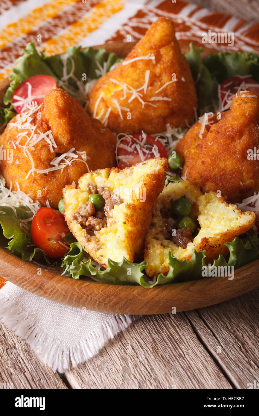 Arancini rice balls with meat and peas close-up on a plate. vertical ...