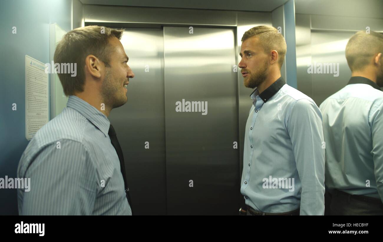 two businessmen riding the Elevator and talking to Stock Photo - Alamy