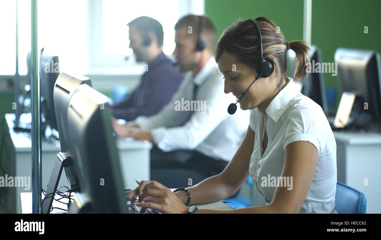 Group of business colleagues with headsets using computers at office ...