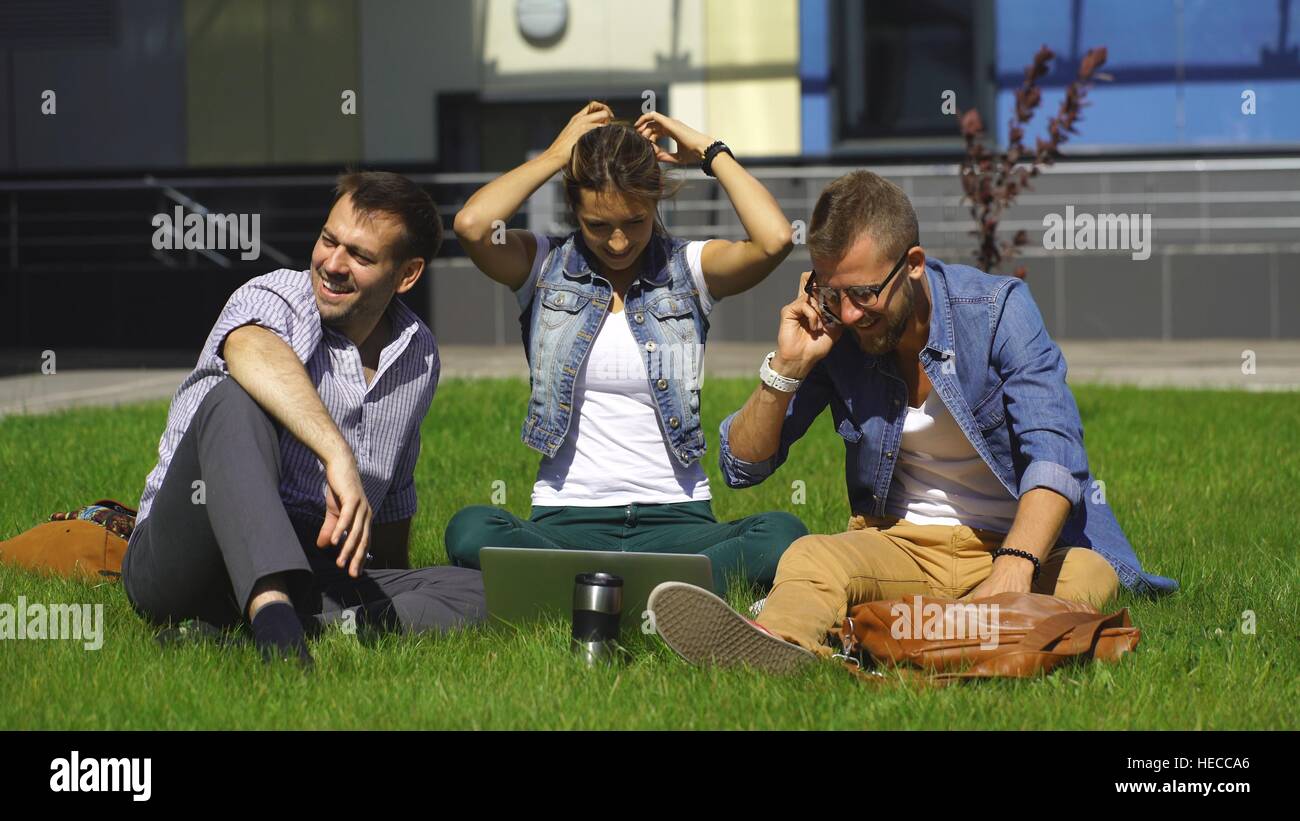 three students sit on the lawn near the University and talking Stock ...