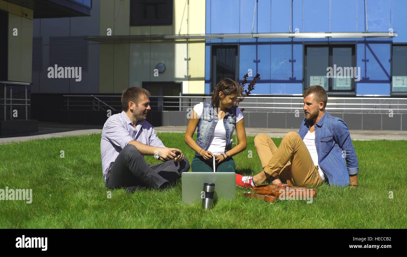 three students sit on the lawn and going to lessons Stock Photo - Alamy