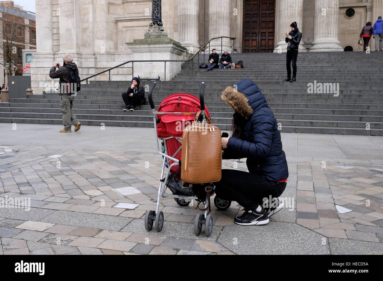 Woman tends to a child in a pushchair on the steps of St Paul's ...