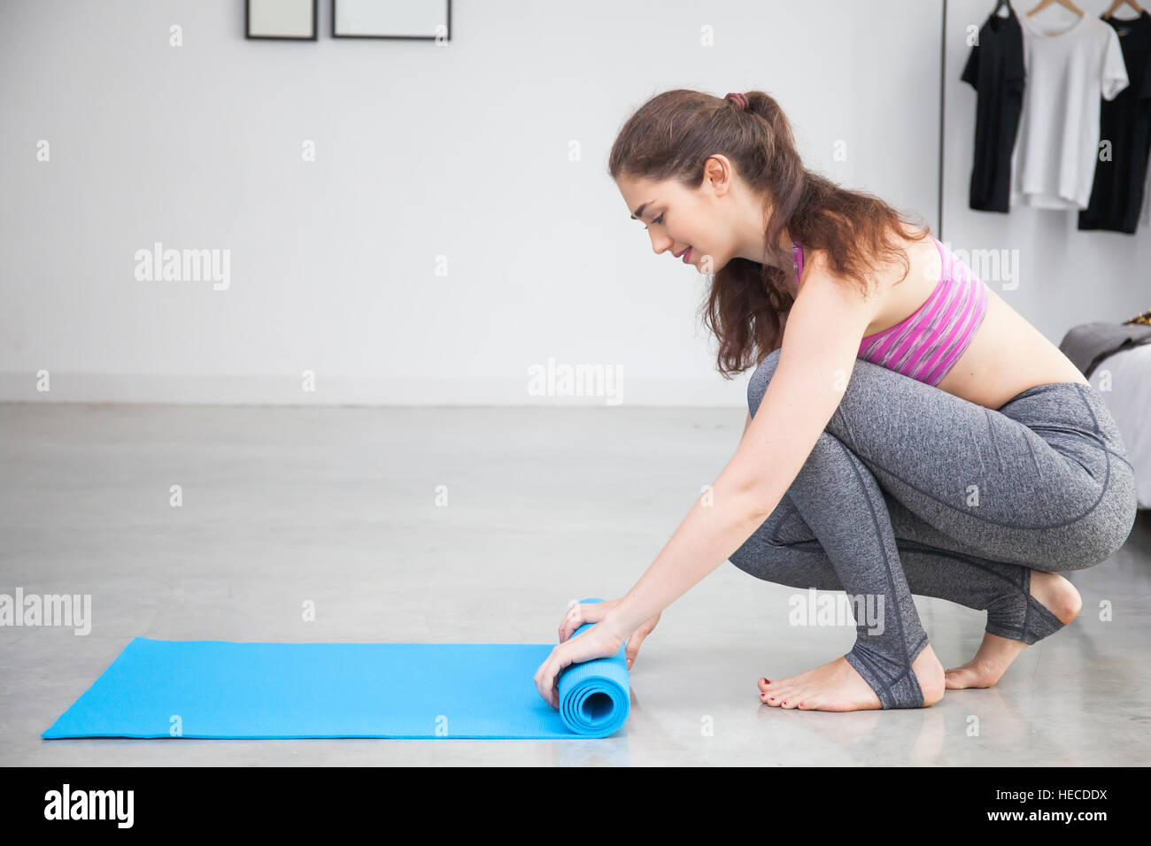 Young Caucasian woman rolling up yoga mat at home studio as she ...