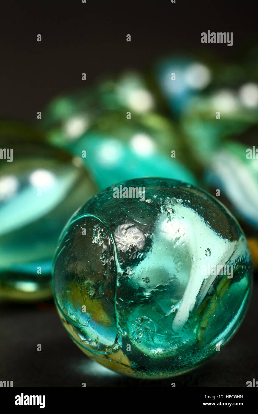 Close up of green toy glass marbles isolated on a black background ...