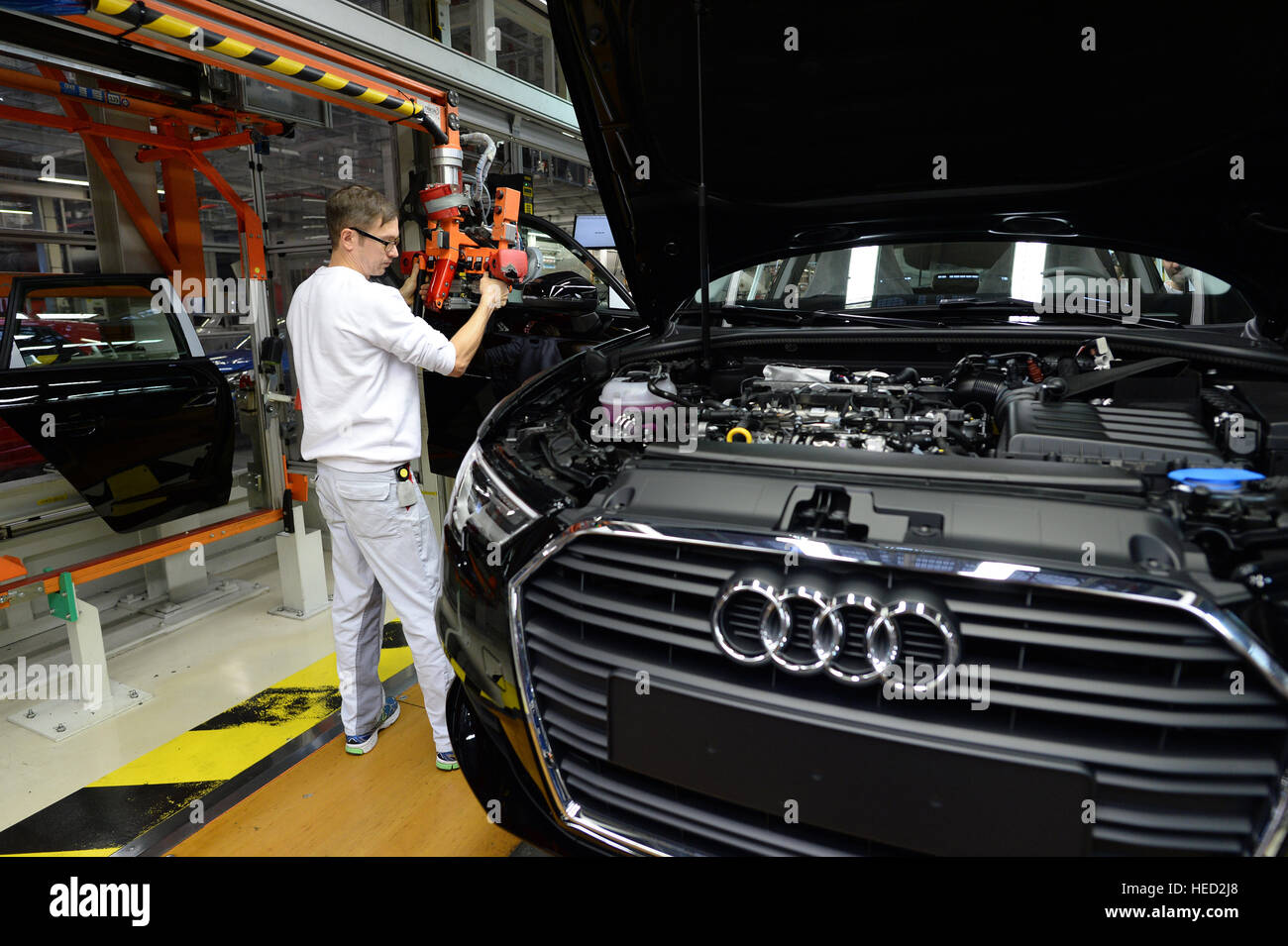 An Audi employee attaches a door to an Audi on an assembly line at the ...