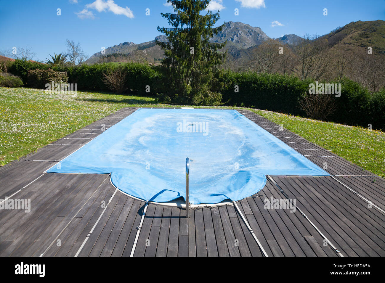 swimming pool with wooden curb closed and covered with blue tarp in ...