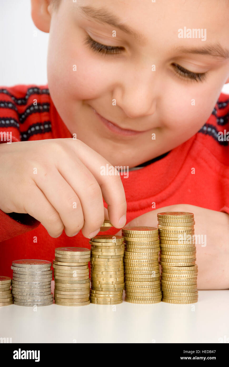 7 year-old boy counting stacks of coins, stacking coins Stock Photo - Alamy