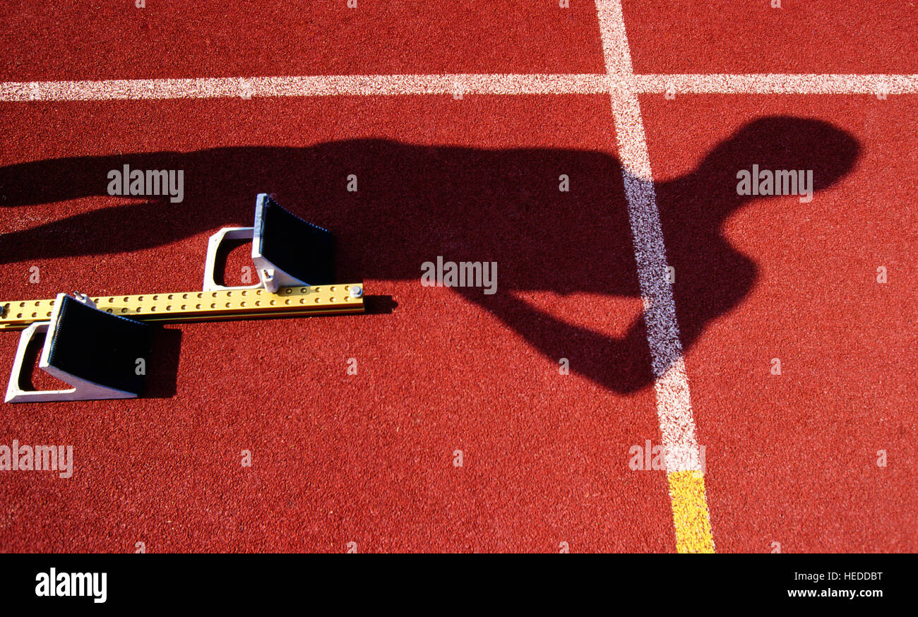 An athlete standing on a red track surface at the starting blocks about ...
