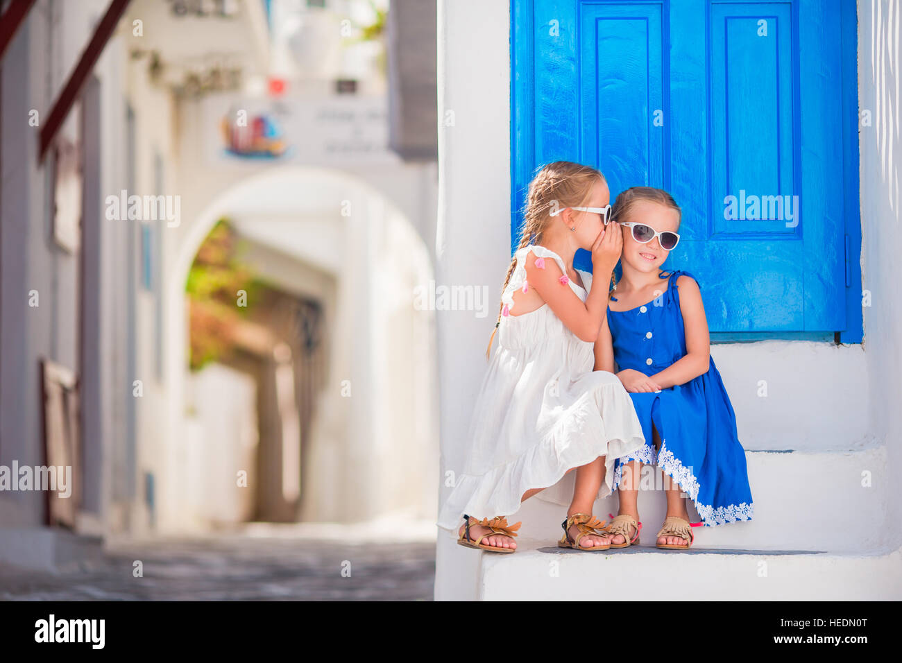 Little girls at street of typical greek traditional village on Mykonos ...