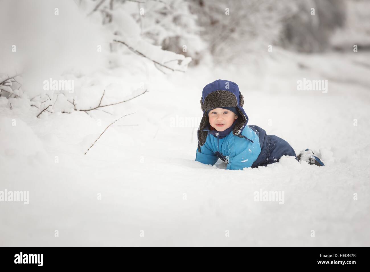 Boy playing in big snow in winter. Happy caucasian child playing in ...