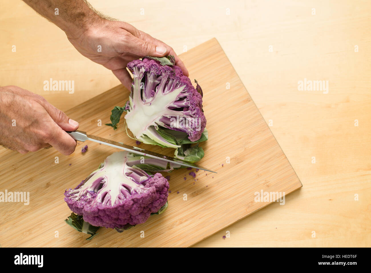 A head of purple cauliflower being sliced open on a cutting board Stock ...