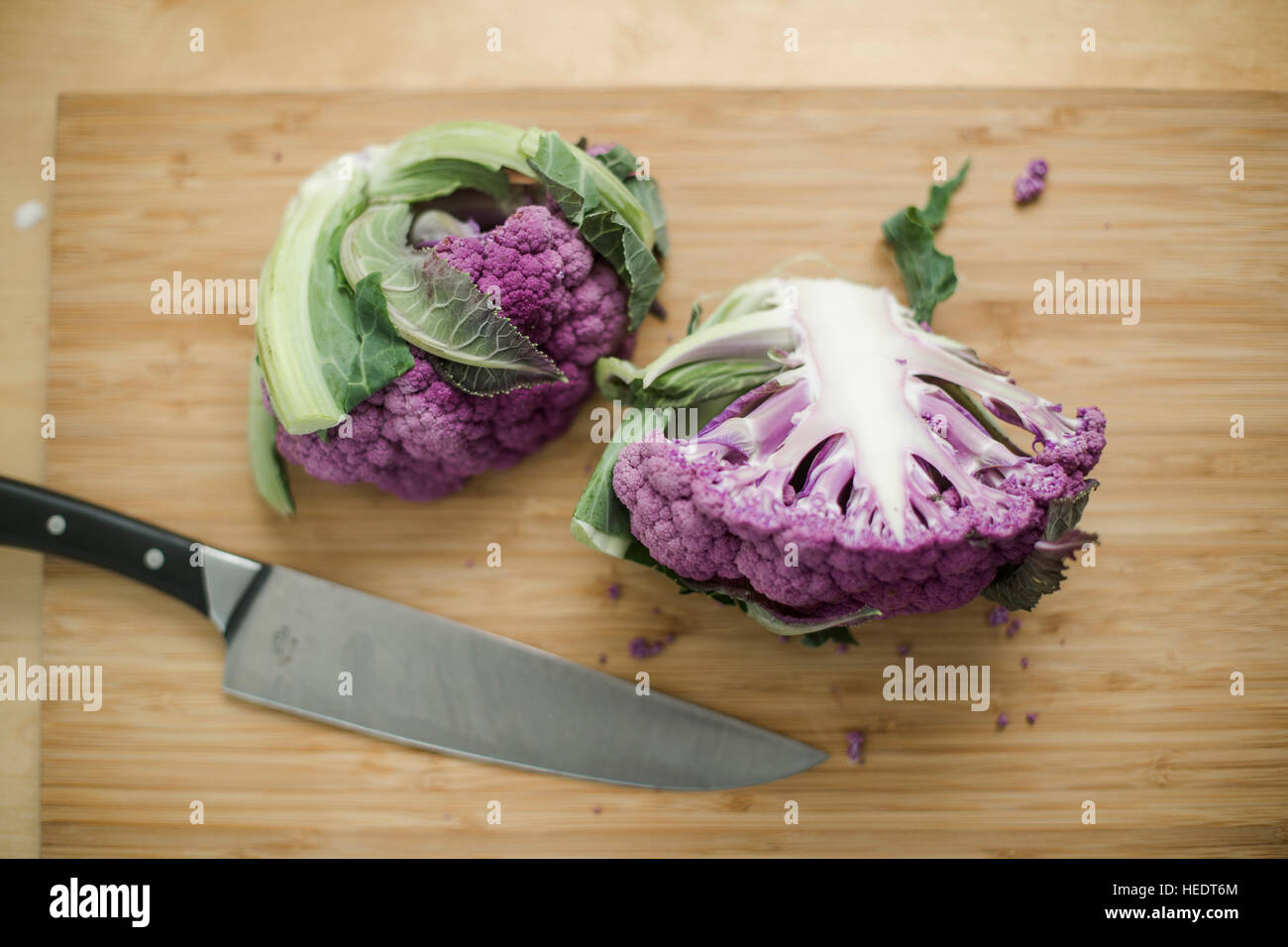 A head of purple cauliflower sliced open on a wooden cutting board ...