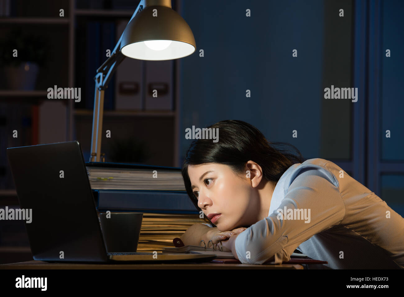 asian business woman sitting at desk sleepy working overtime late night. indoors office ...