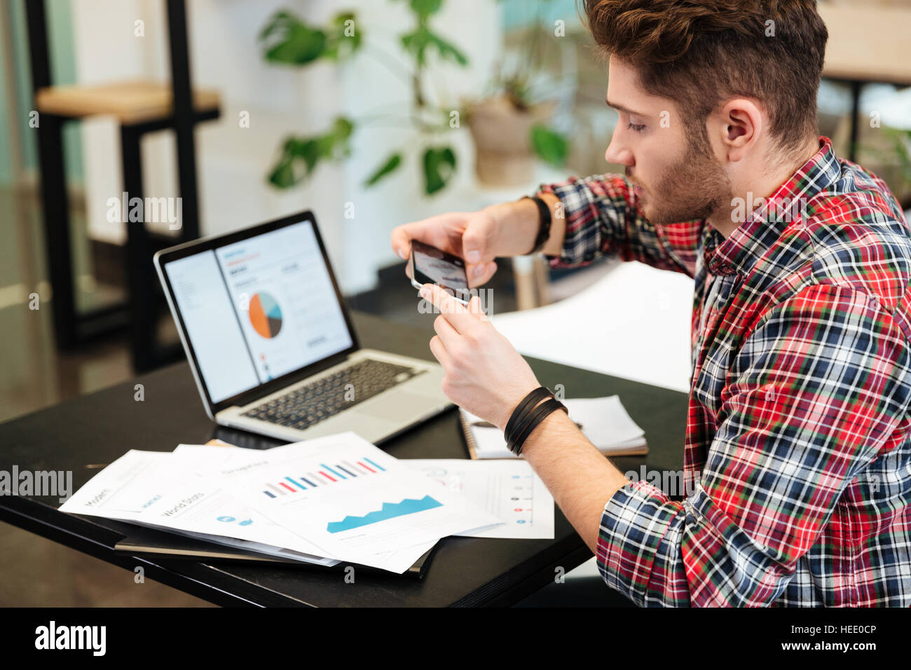 Side view of man sitting at the table with documents and making photo ...