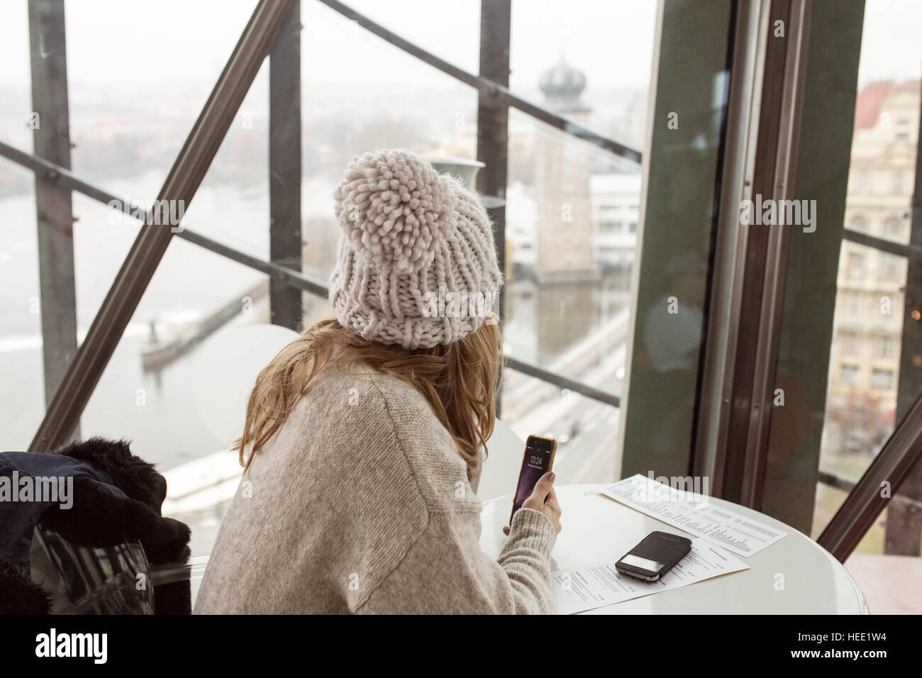 Woman sitting and watching city through window Stock Photo - Alamy