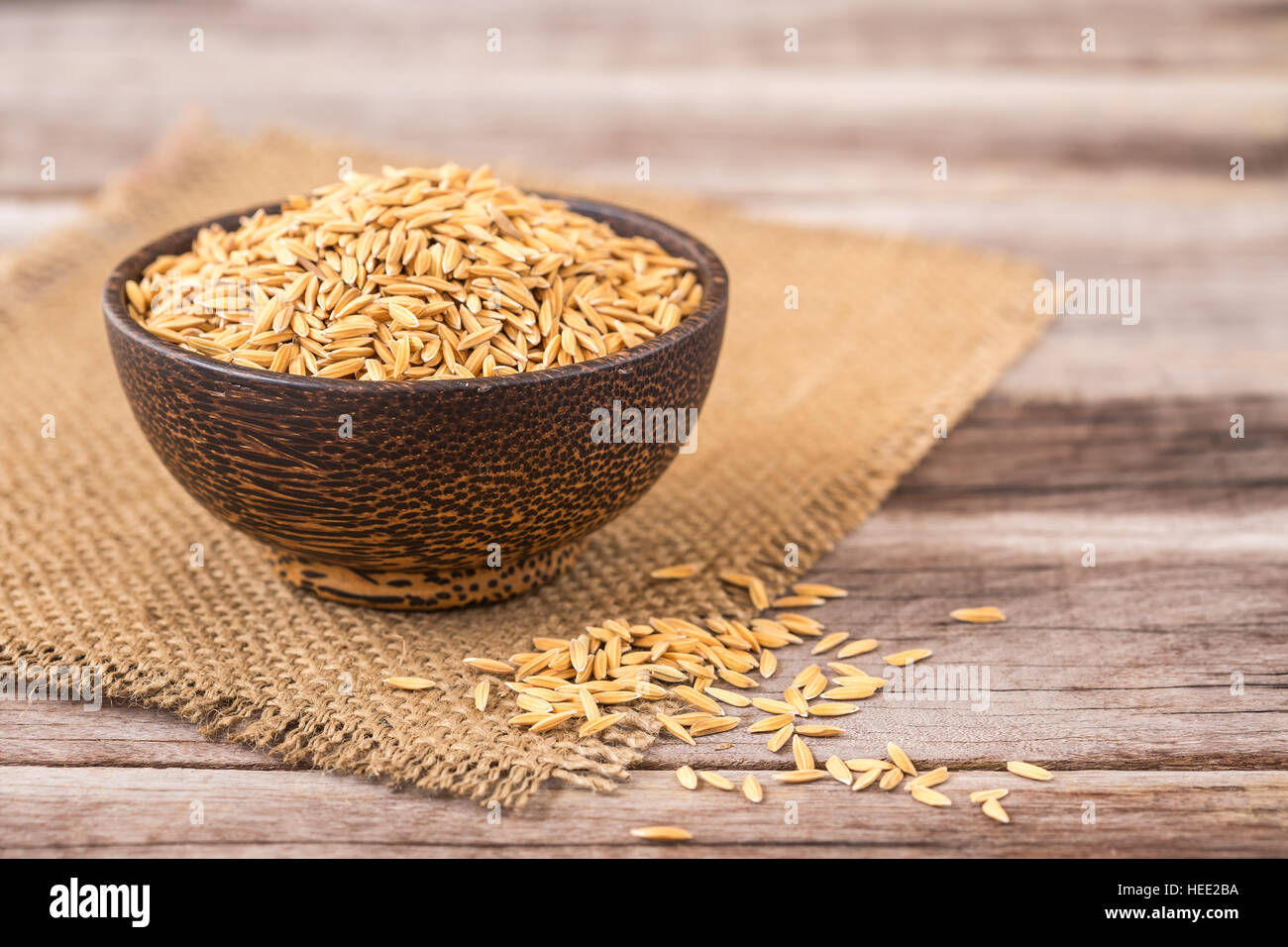 Yellow Thai paddy jasmine rice on wooden plank background Stock Photo ...