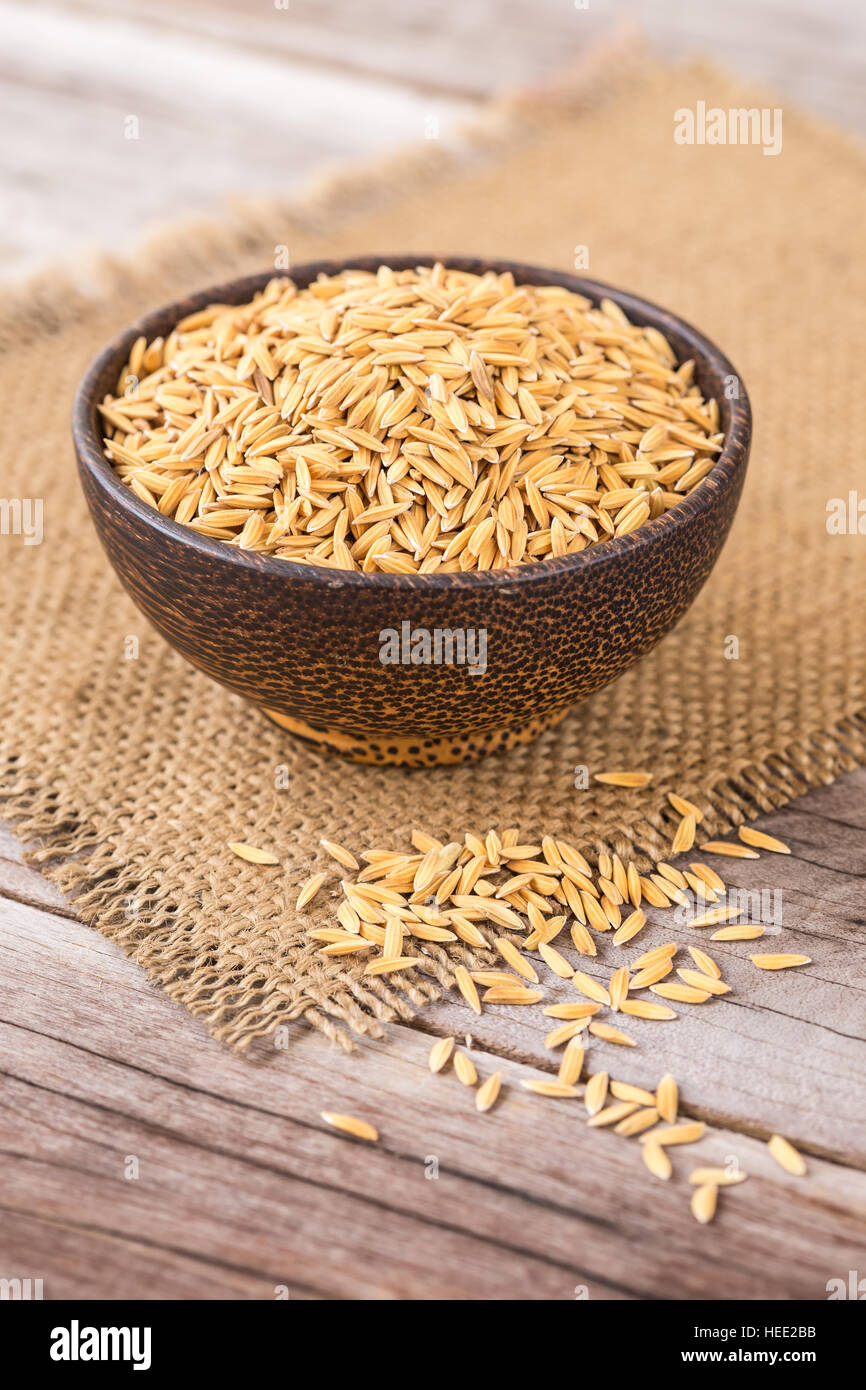 Yellow Thai paddy jasmine rice on wooden plank background Stock Photo ...