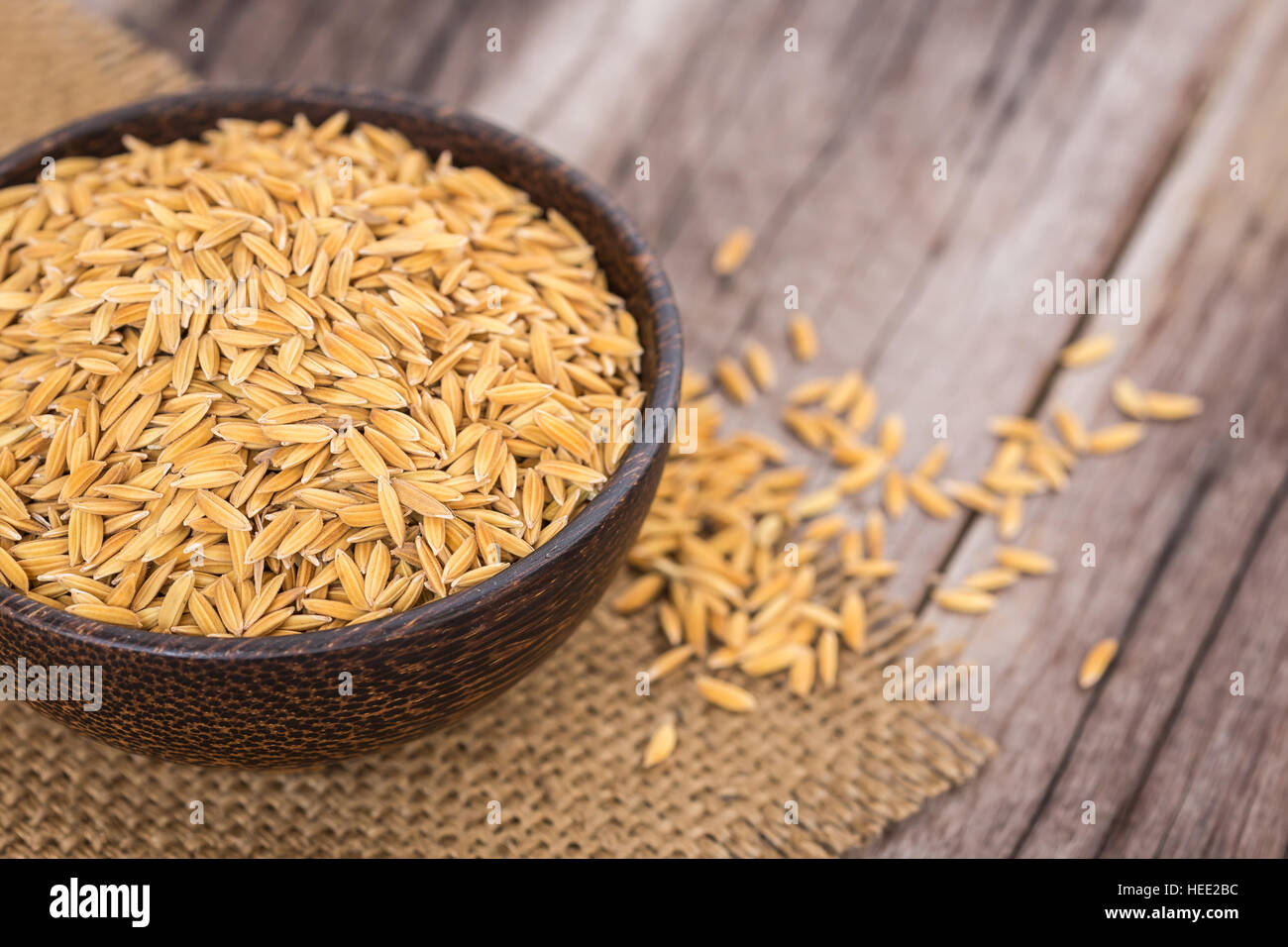Yellow Thai paddy jasmine rice on wooden plank background Stock Photo ...