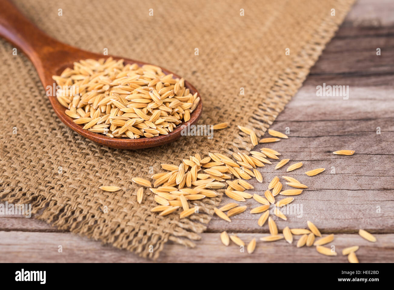 Yellow Thai paddy jasmine rice on wooden plank background Stock Photo ...