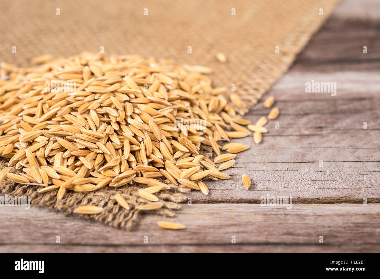 Yellow Thai paddy jasmine rice on wooden plank background Stock Photo ...