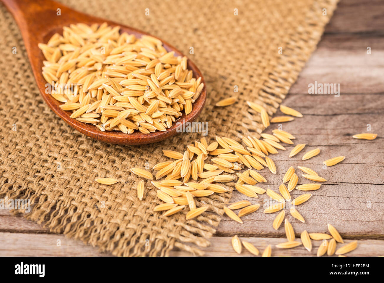 Yellow Thai paddy jasmine rice on wooden plank background Stock Photo ...