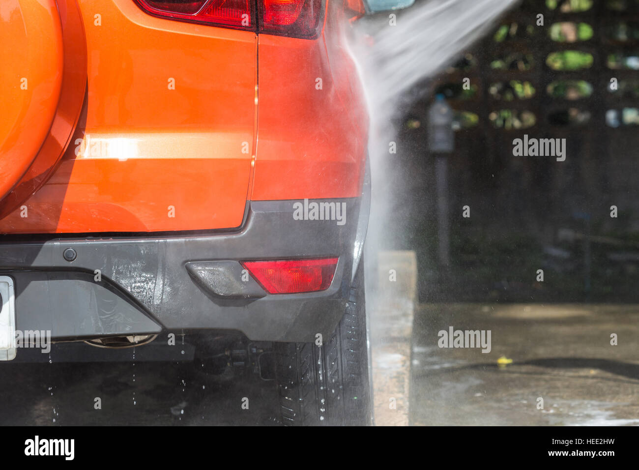 A man spraying pressure washer for car wash in car care shop. Focus on ...