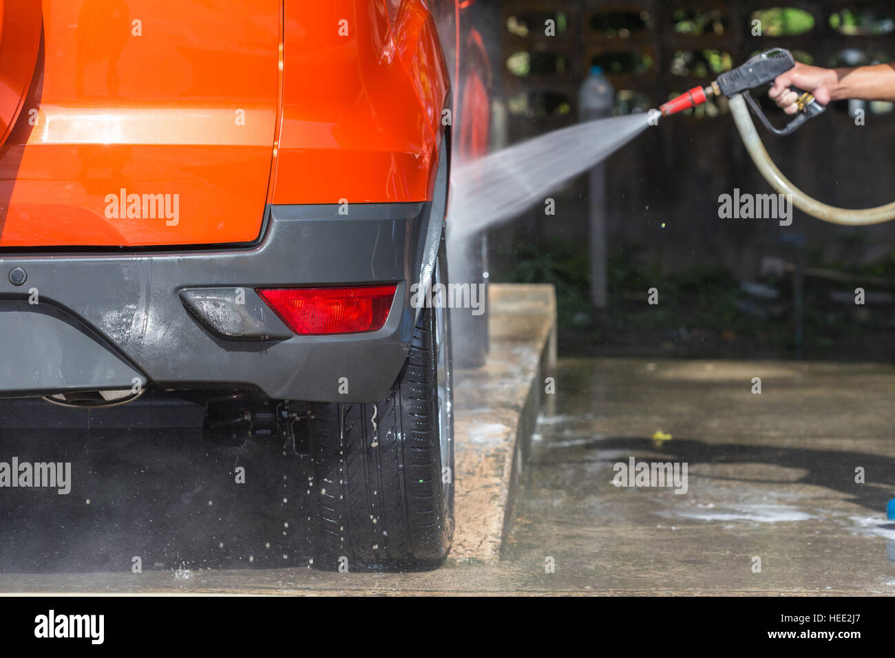 A man spraying pressure washer for car wash in car care shop. Focus on ...