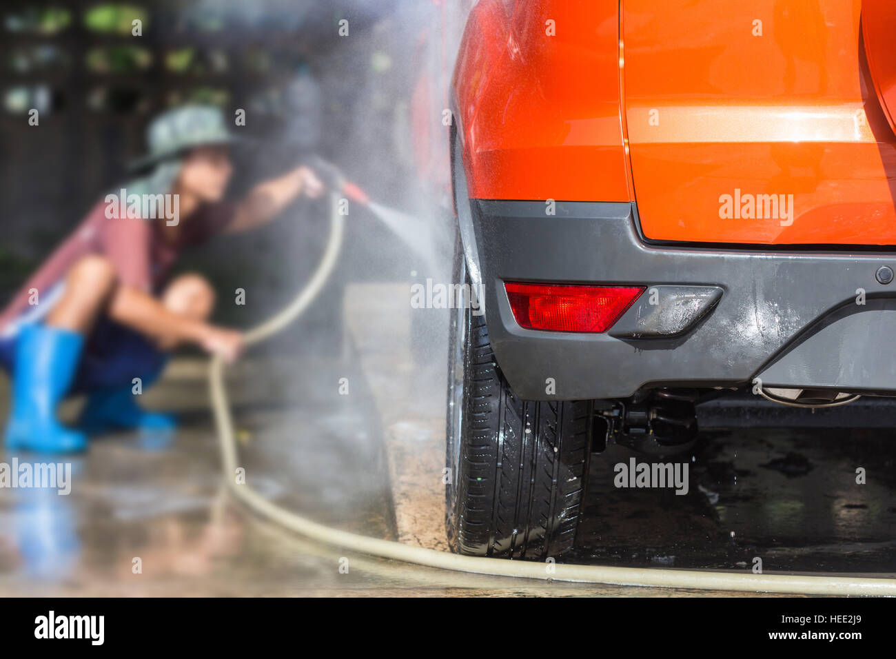 A man spraying pressure washer for car wash in car care shop. Focus on ...