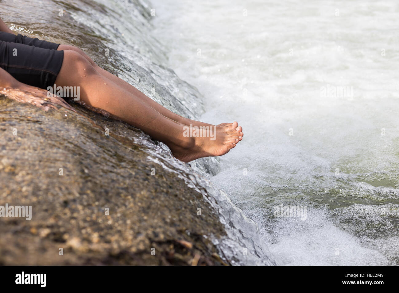 Woman sitting at waterfall. Focus on leg Stock Photo - Alamy