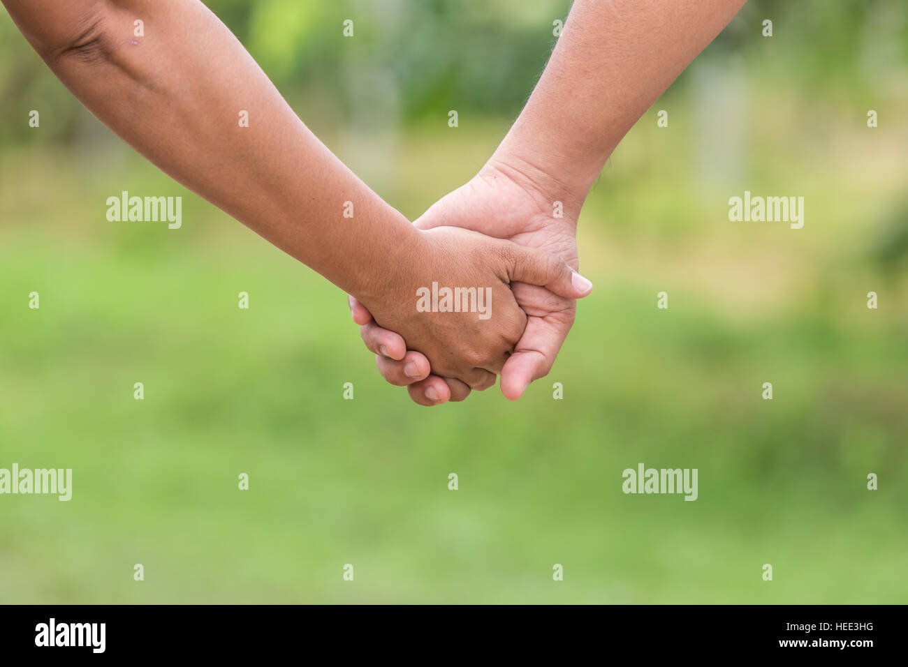 Two hands holding together. Help or support concept. On green blur ...