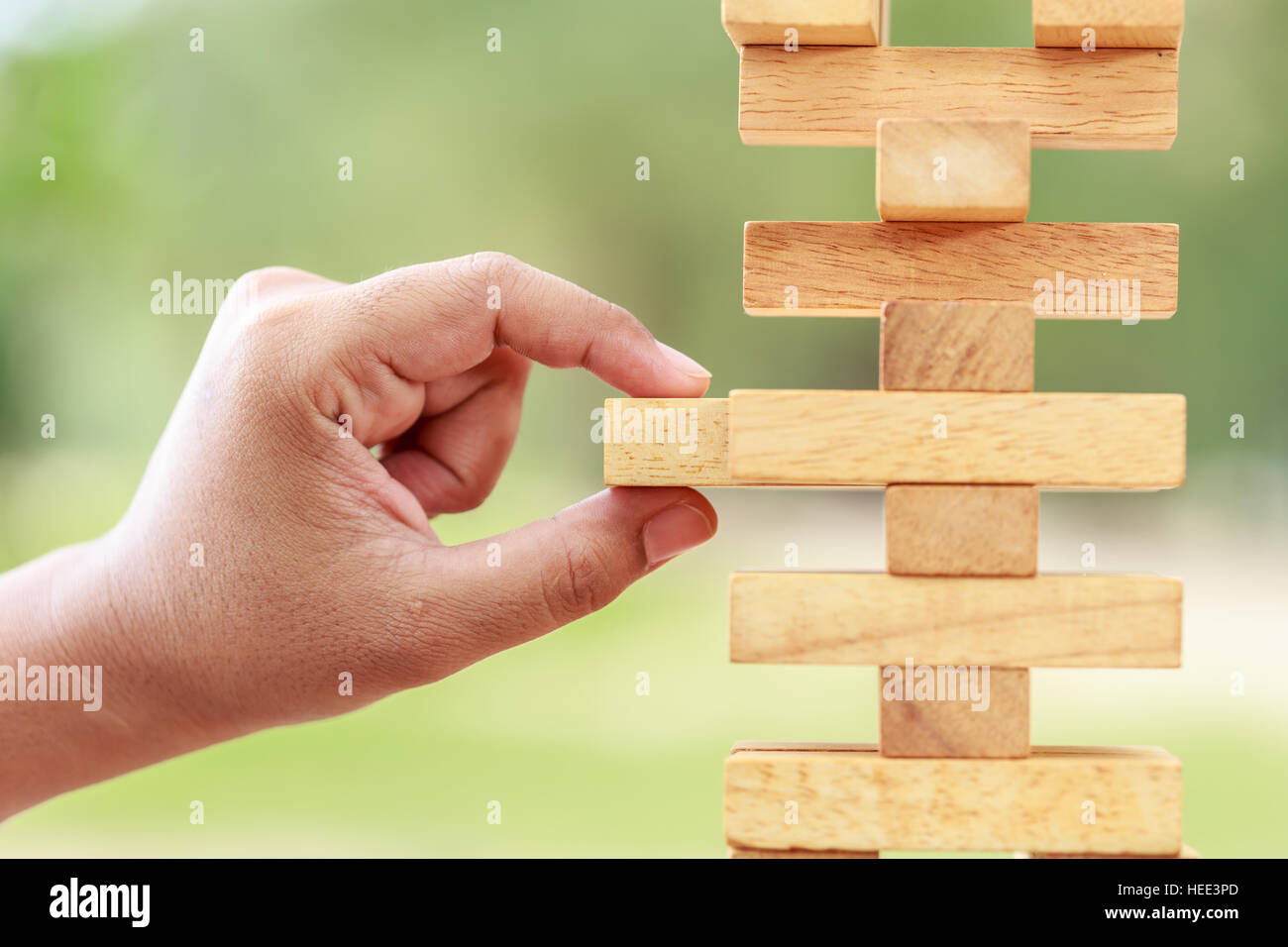 Close up hand holding blocks wood game (jenga) on blurred green ...