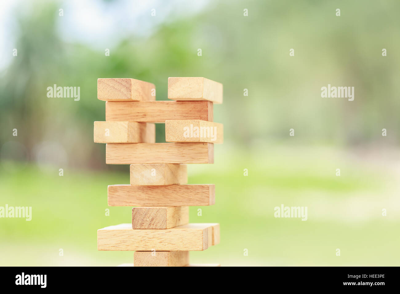 Close up hand holding blocks wood game (jenga) on blurred green ...