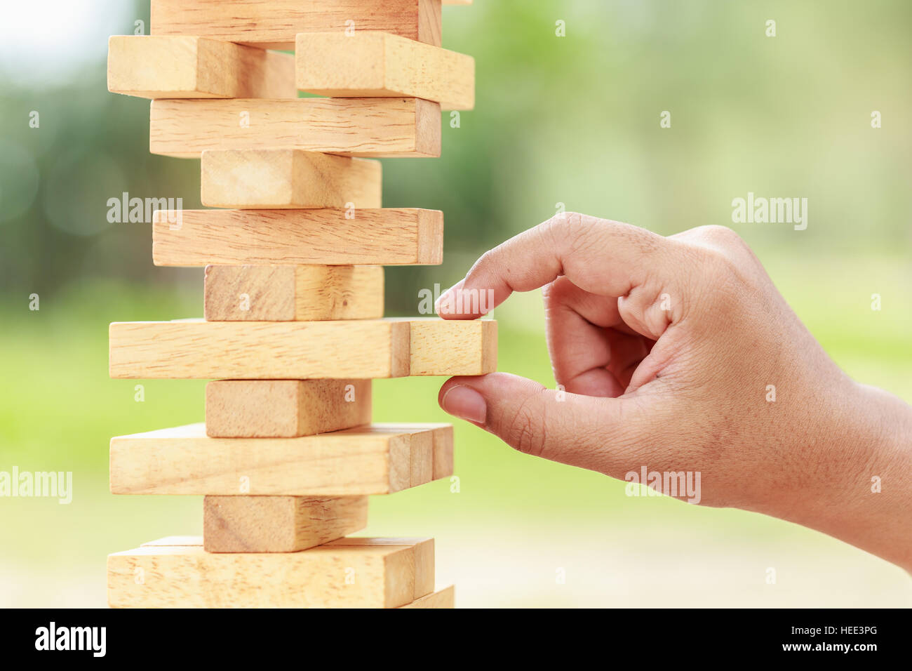 Close up hand holding blocks wood game (jenga) on blurred green ...