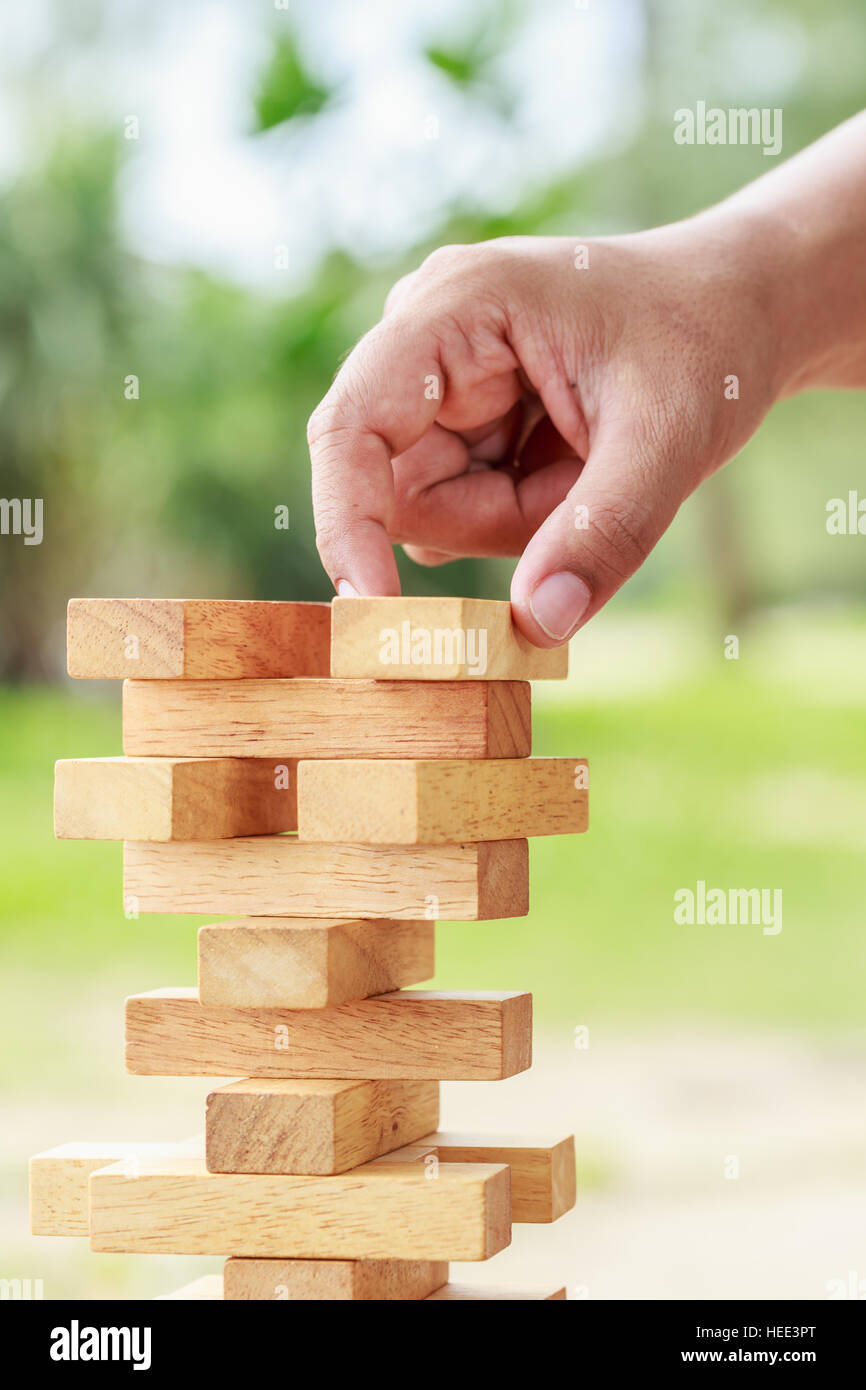 Close up hand holding blocks wood game (jenga) on blurred green ...